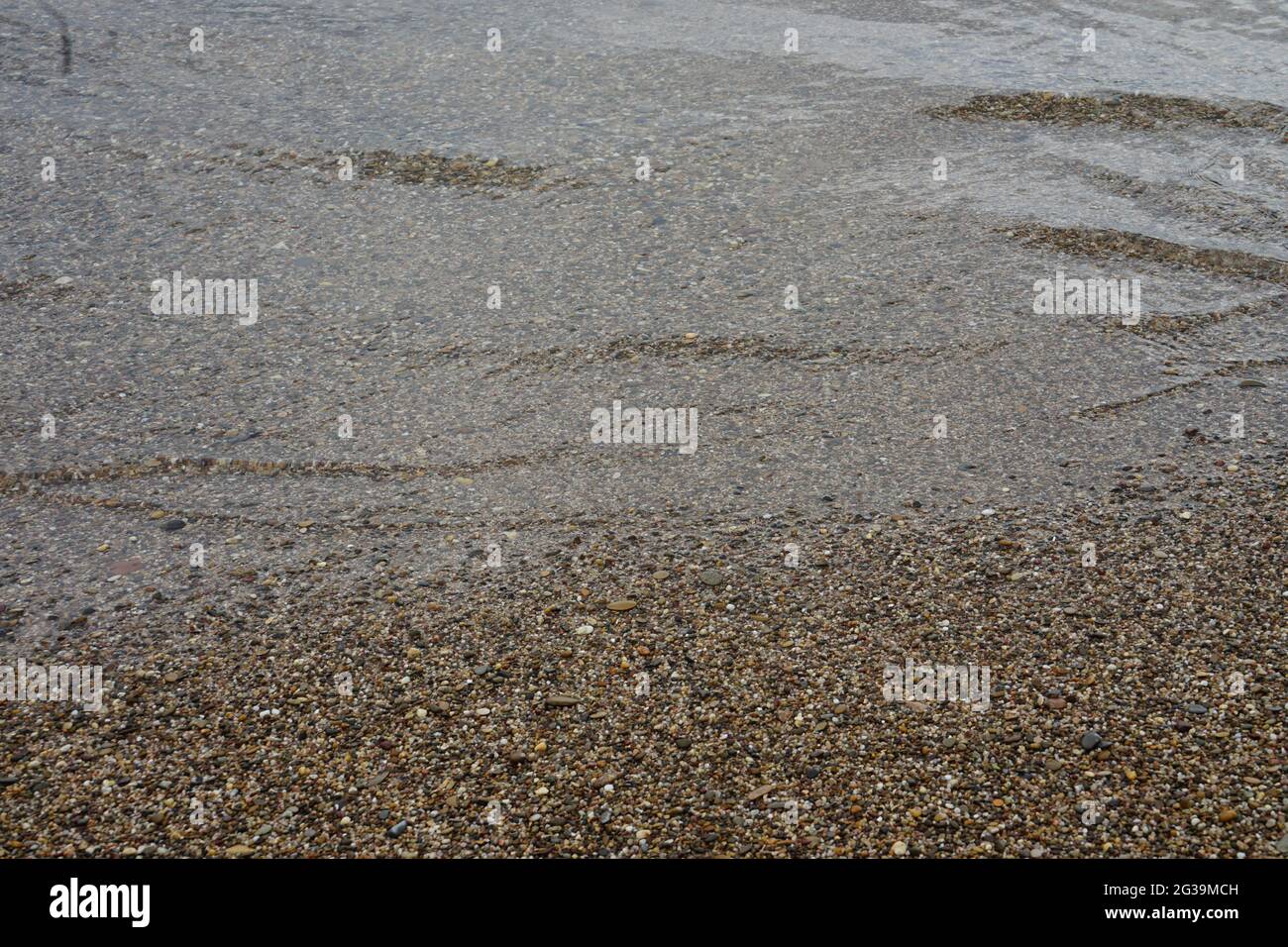 Closeup of waves washing the shore full of small stones Stock Photo - Alamy