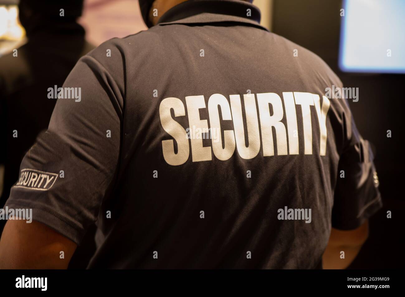 Rear view of a security guard in uniform patrolling in a commercial ...
