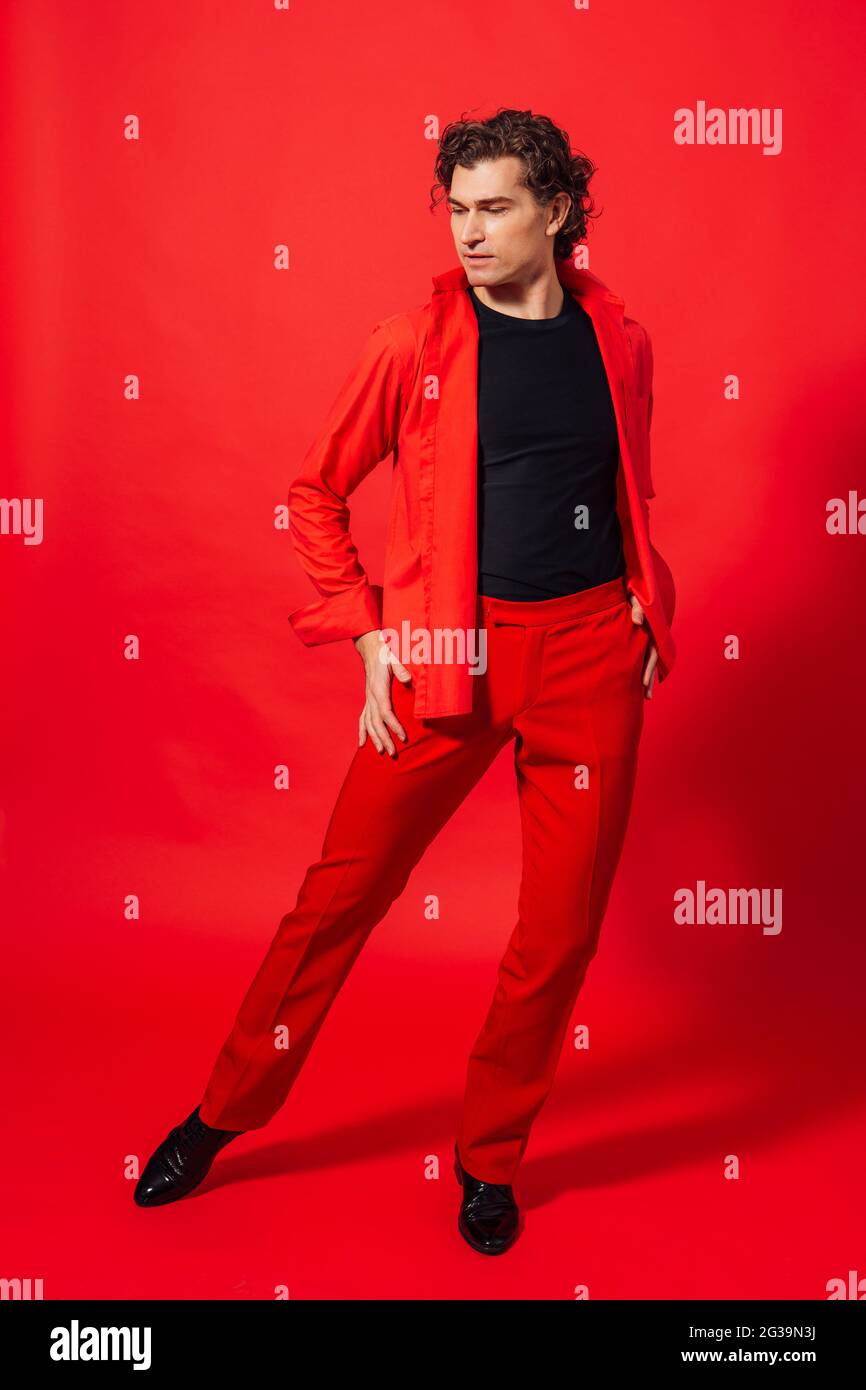 Portrait of a tall handsome man dressed in red shirt posing on the red ...