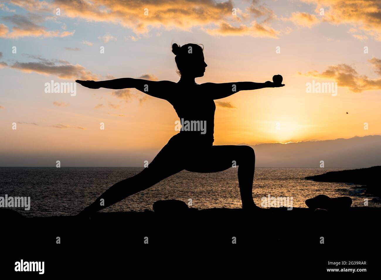Silhouette of a woman on the beach during sunset, stretching and ...
