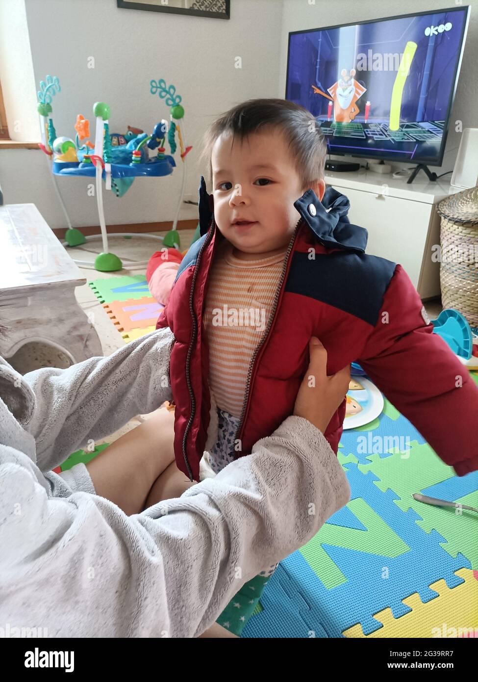 Vertical shot of a multiracial baby in a kid's room supported by a ...