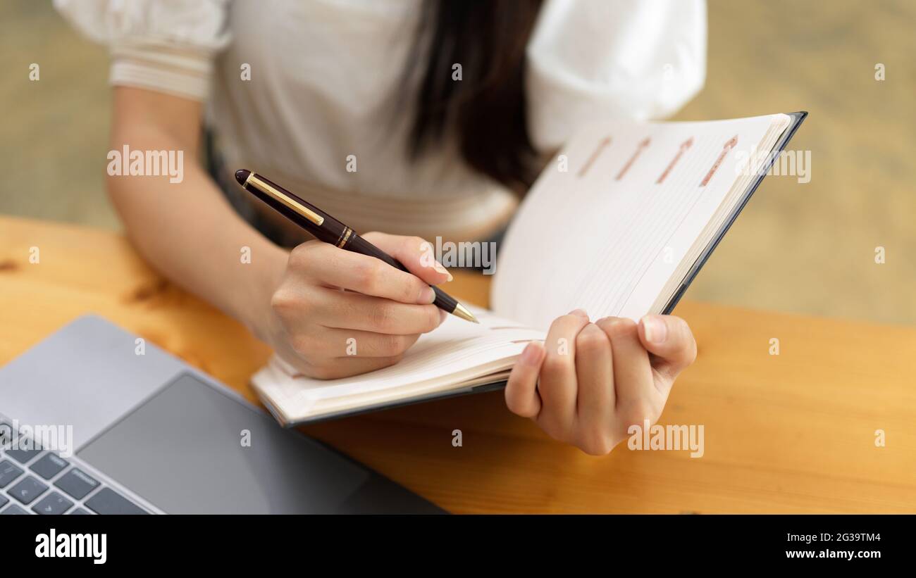 Close up view of female handwriting on schedule book while working with ...