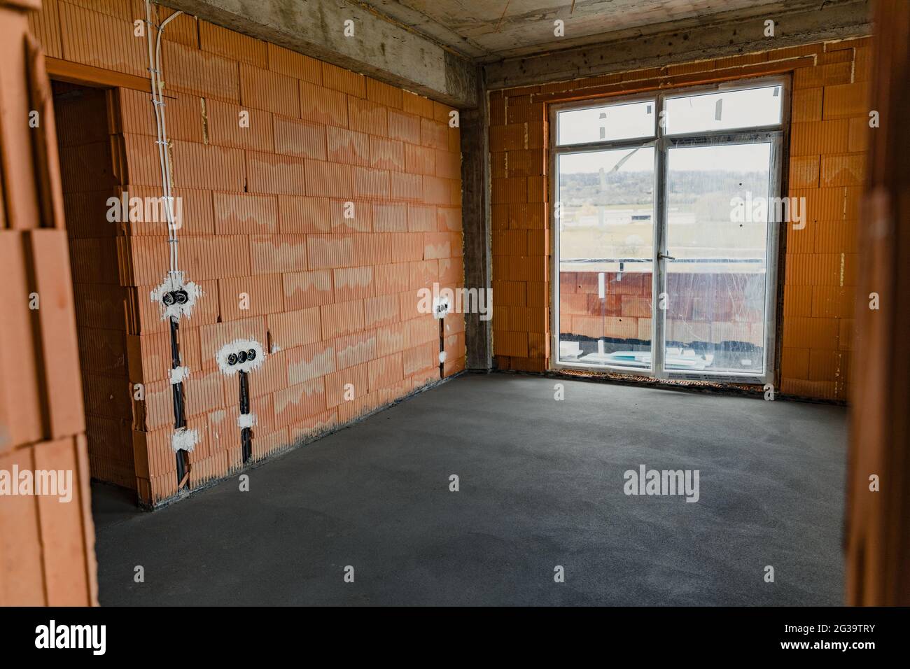 Indoor construction site with a big window, brown bricks and concrete ...