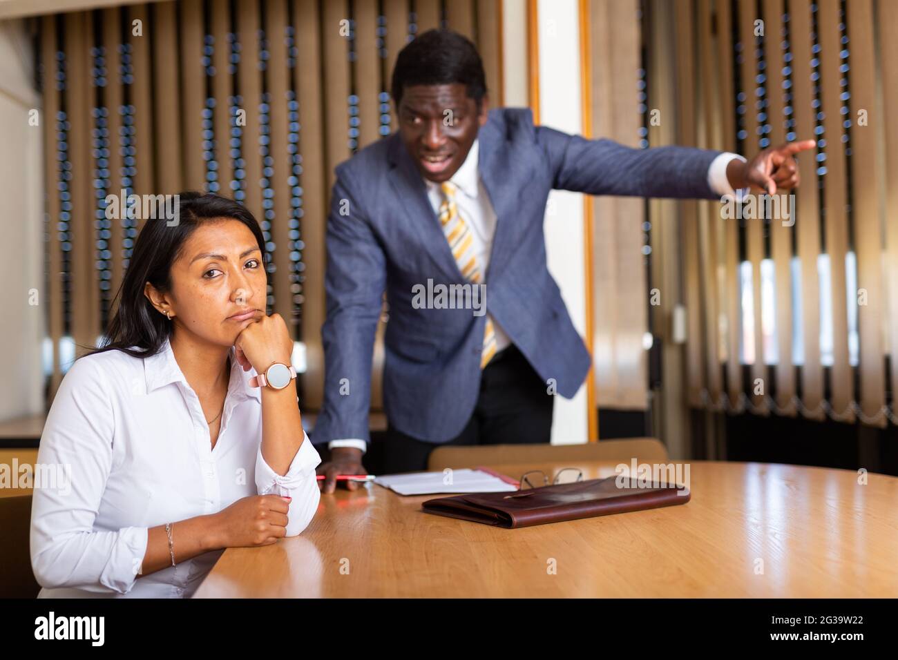 Upset woman sitting in office with disgruntled boss behind Stock Photo ...