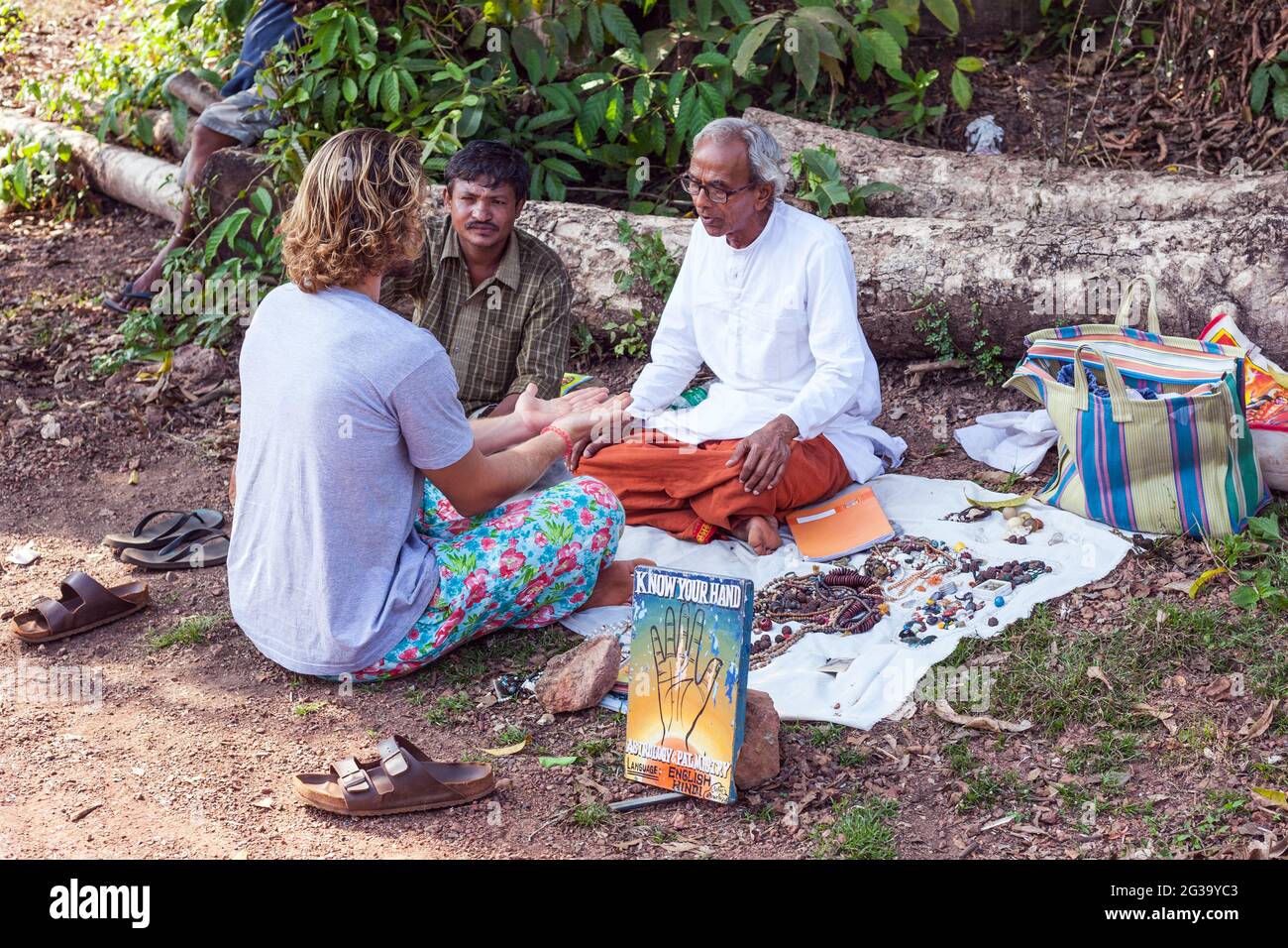 Western male tourist with long hair sits in lotus position having his ...