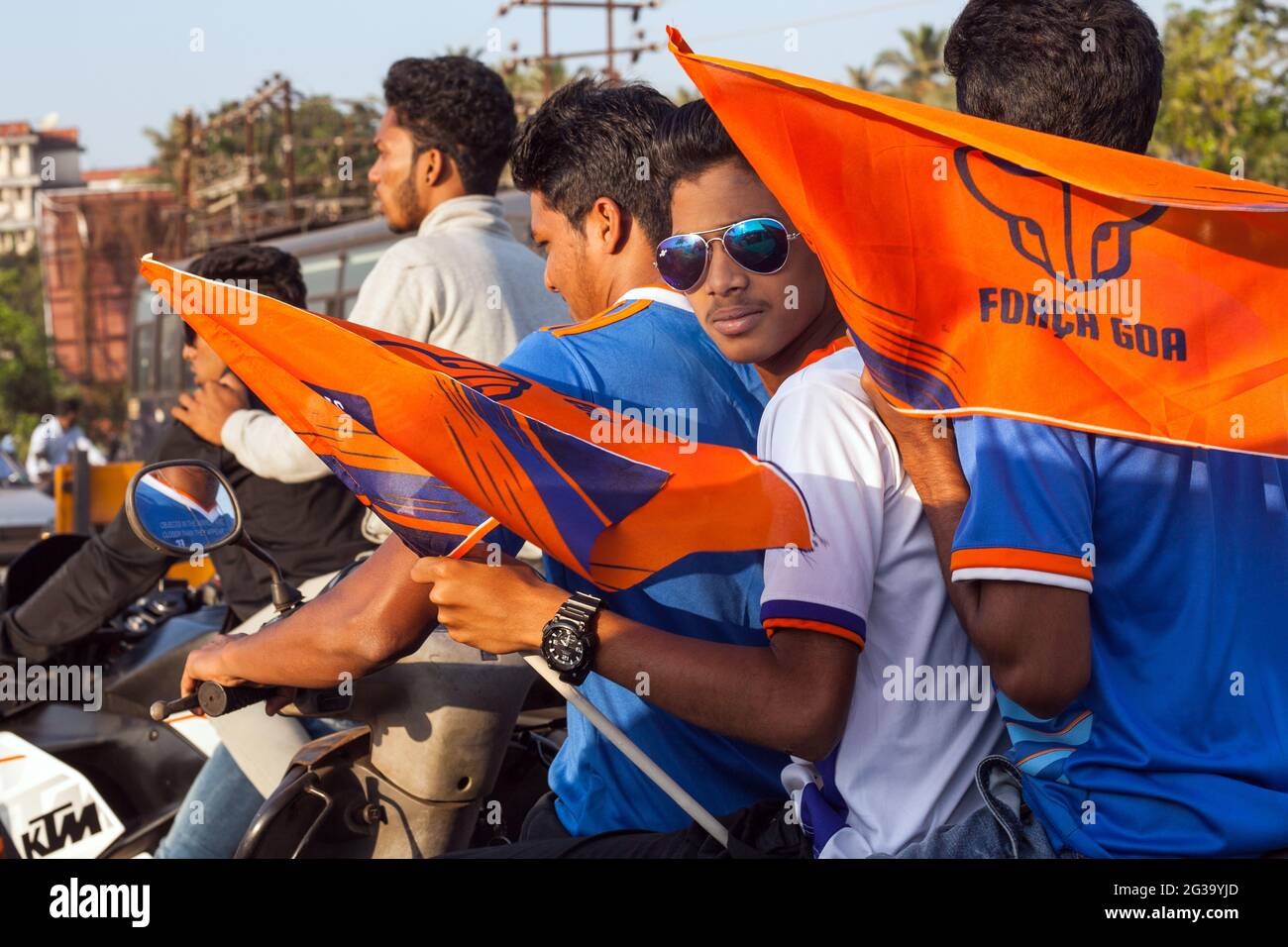 Three cheerful Indian males wave flags heading for FC Goa football ...