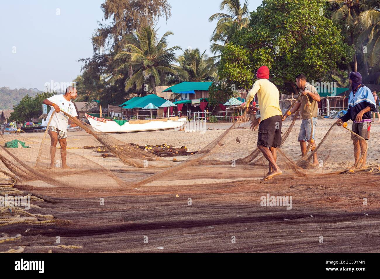 Indian fishermen tending to their fishing nets on the beach, Agonda ...