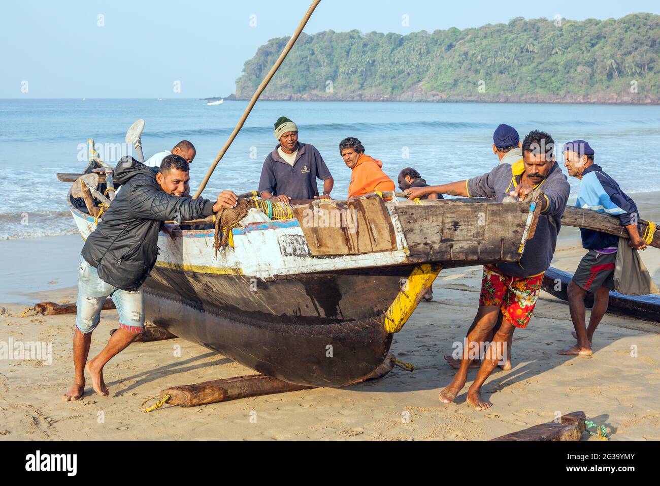Indian fishermen returning from their fishing trip pull fishing boat on ...