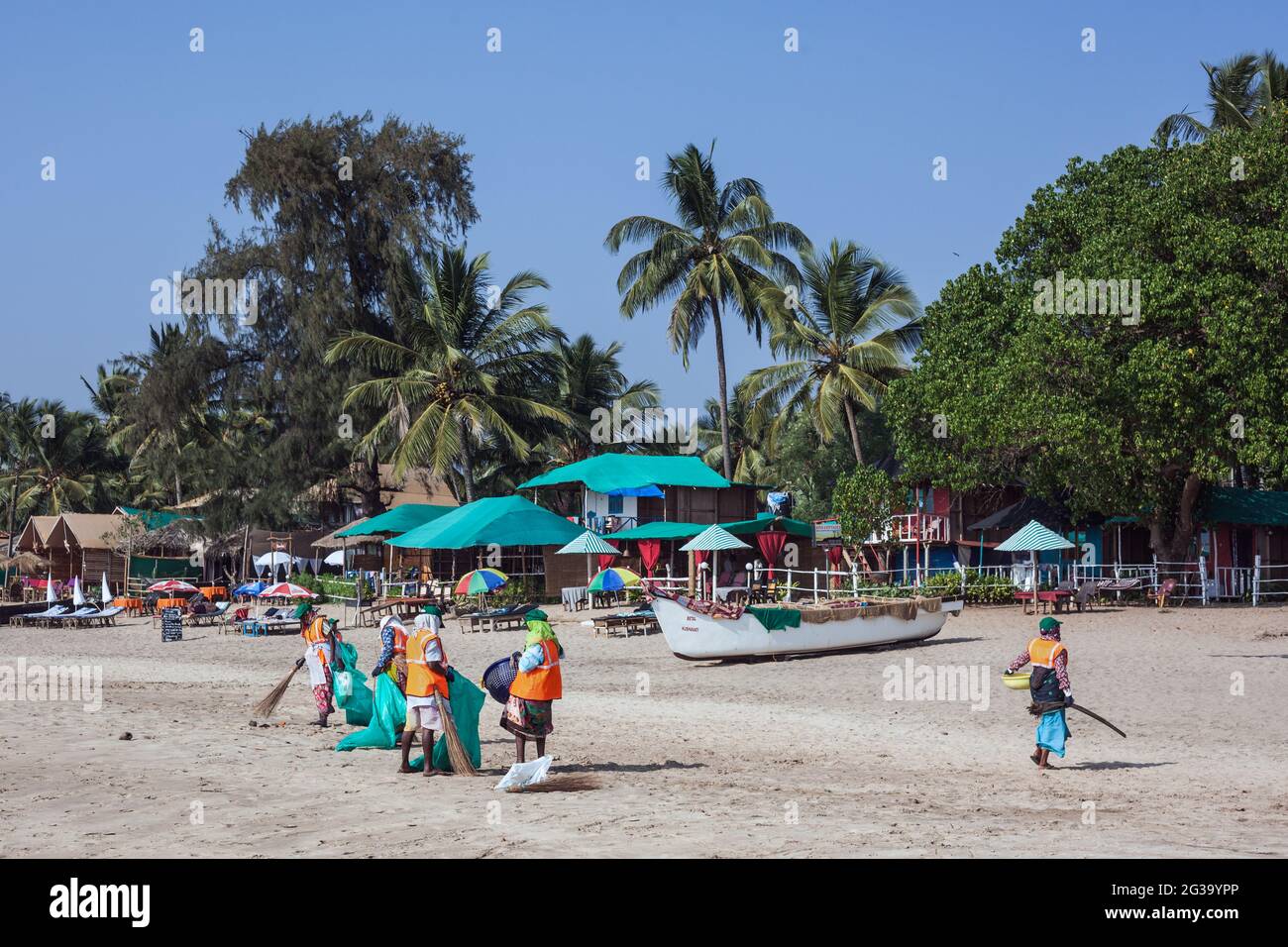 Indian beach cleaners wearing high vis vests collecting rubbish from ...