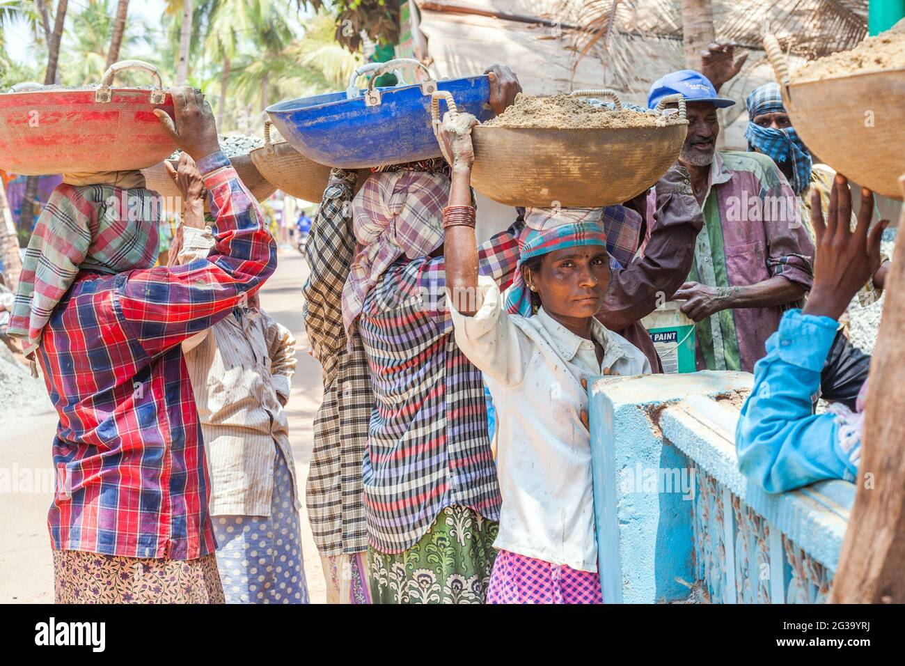Female Indian manual labour worker carrying heavy load on her head ...