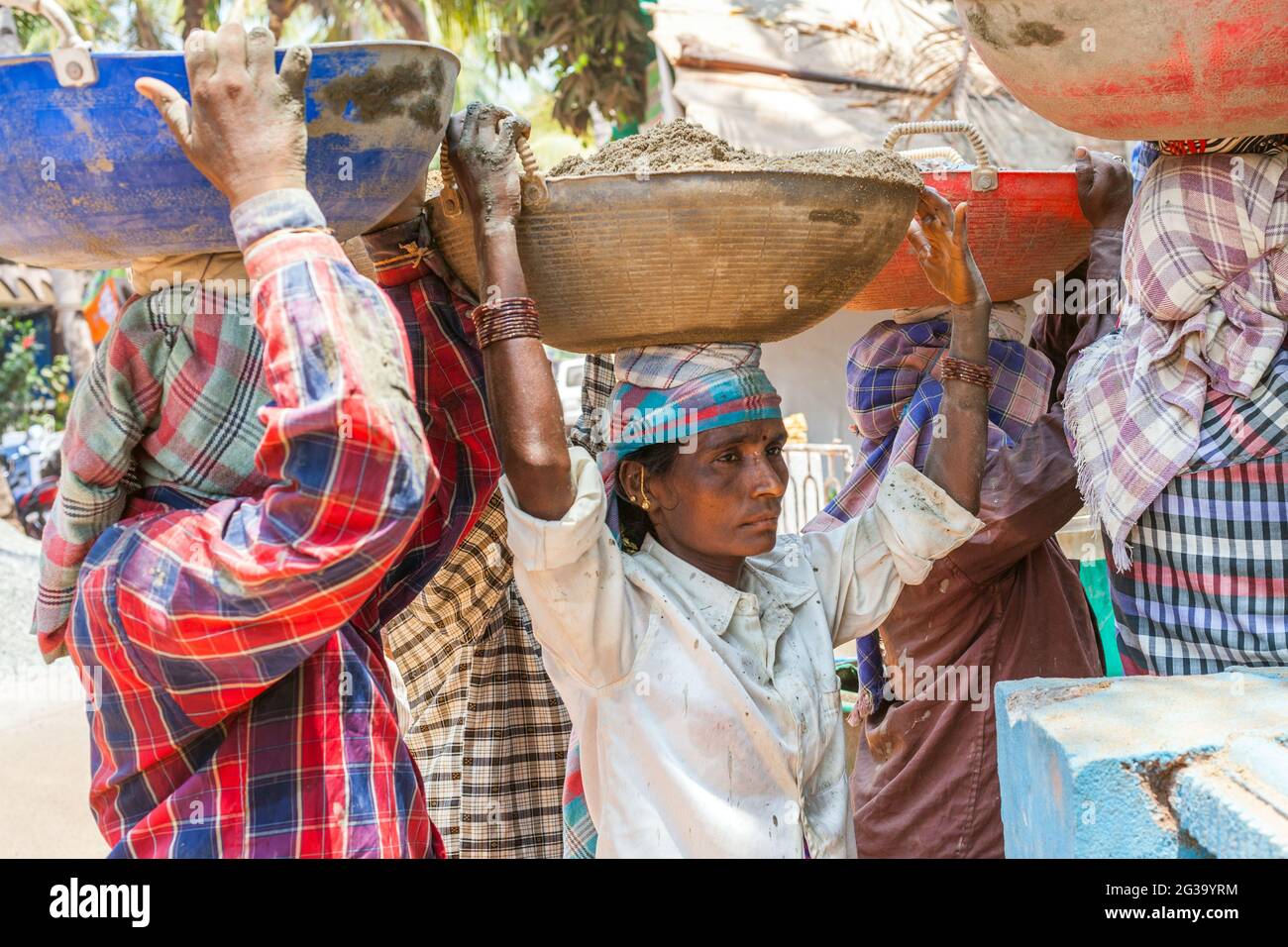 Female Indian manual labour workers carrying heavy loads on their heads ...