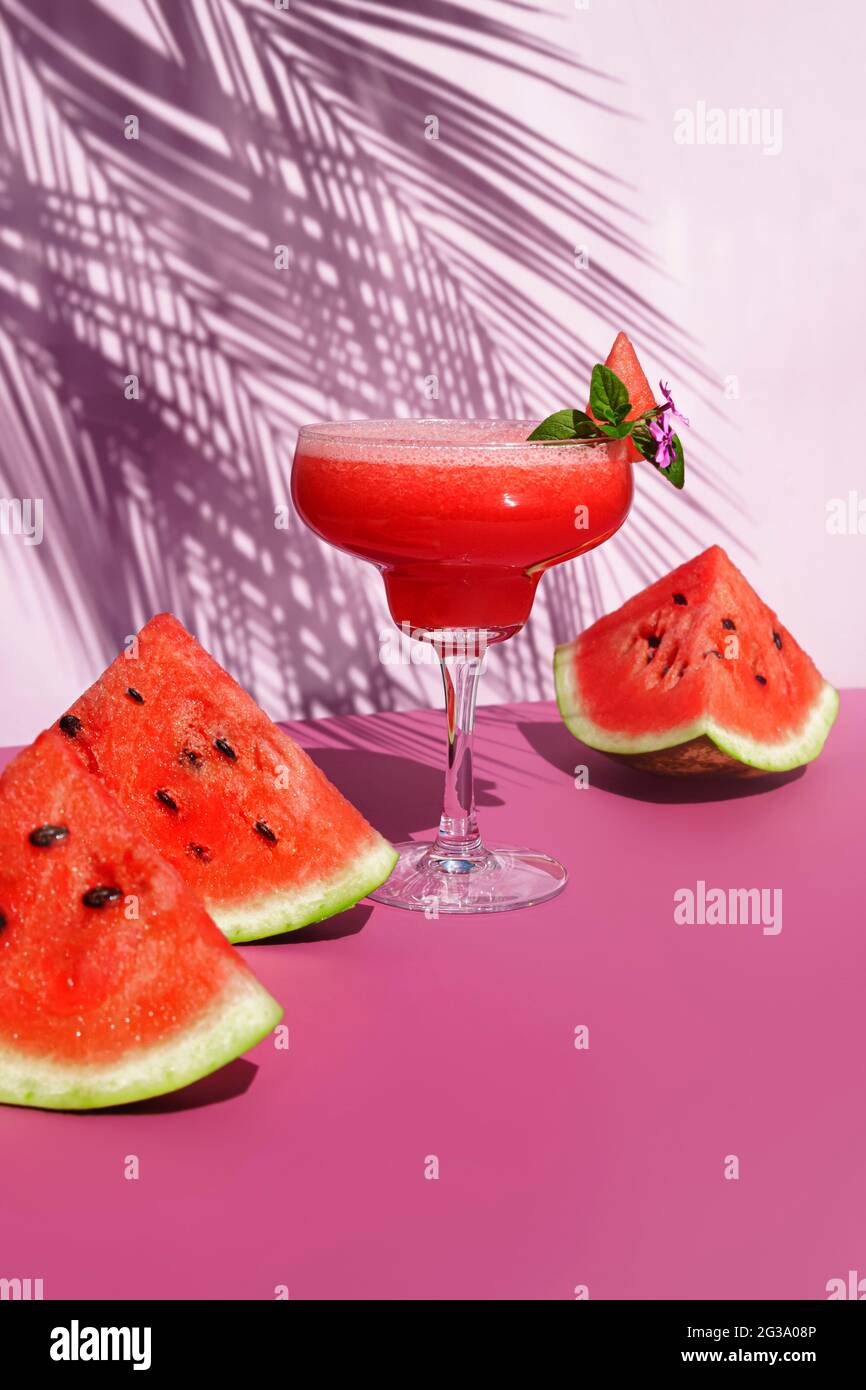 Watermelon cocktail on the table with sun shadows. On a pink background ...