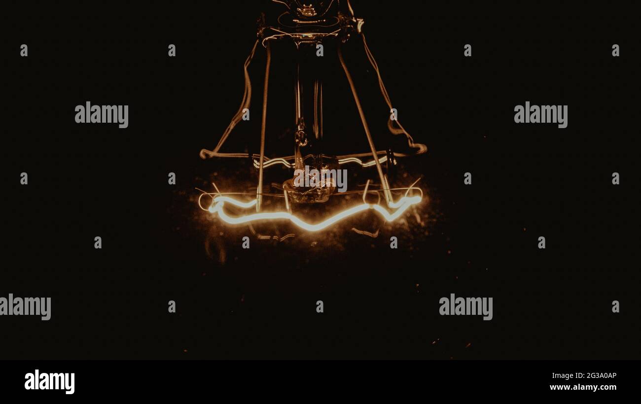 Closeup of a lightbulb with its glass shattered, giving dim orange ...