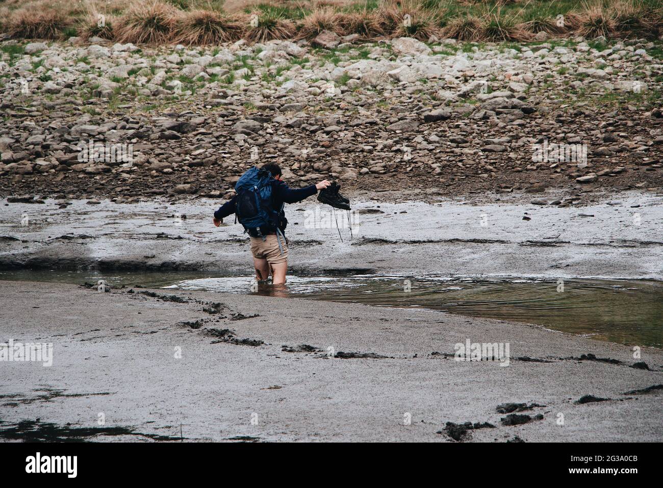 Unhappy traveler with a backpack holding his boots in his hand while ...