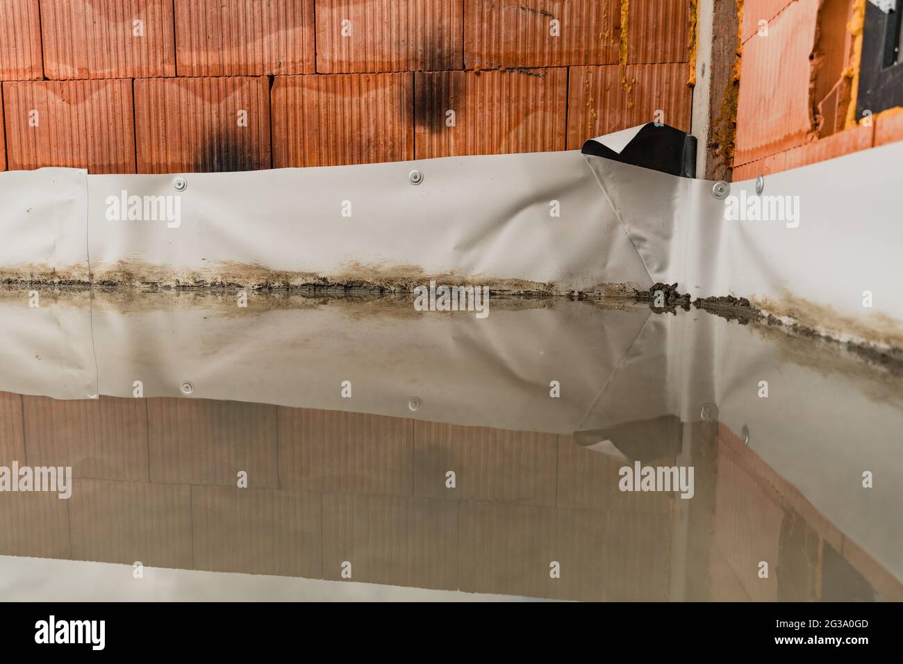 Building wall with brown bricks and wet, reflective ground ...