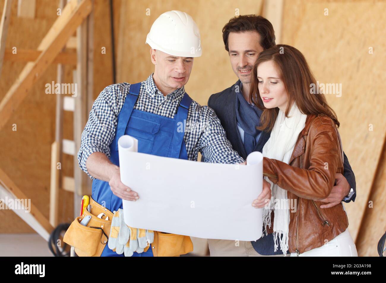 Foreman showing house design construction plan to a happy young couple ...