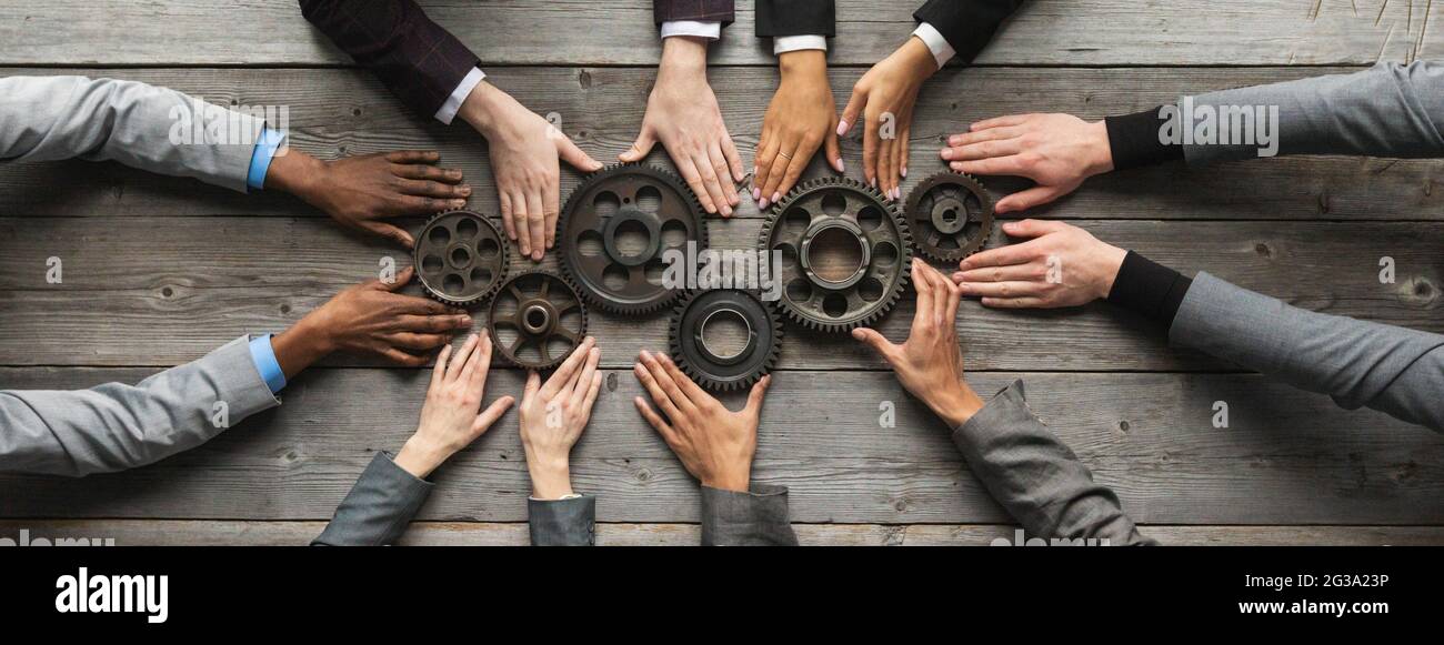 Business people connect gear together at meeting table, success ...