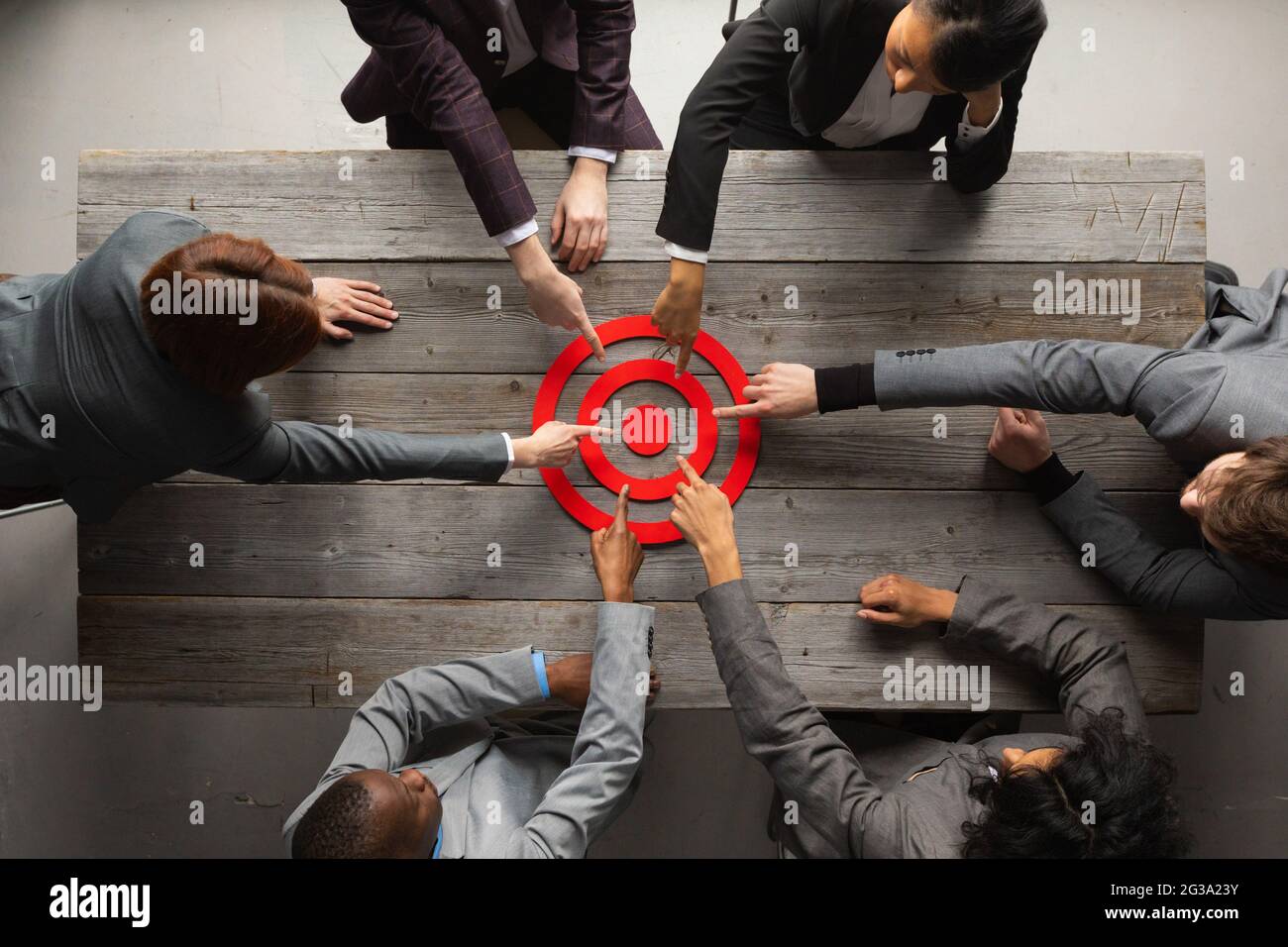 Team of business people pointing at red target at meeting table Stock ...