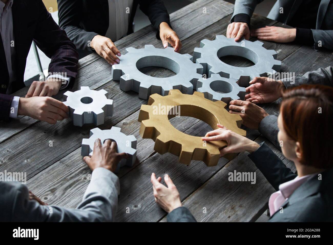 Business people connect gear together at meeting table, success ...
