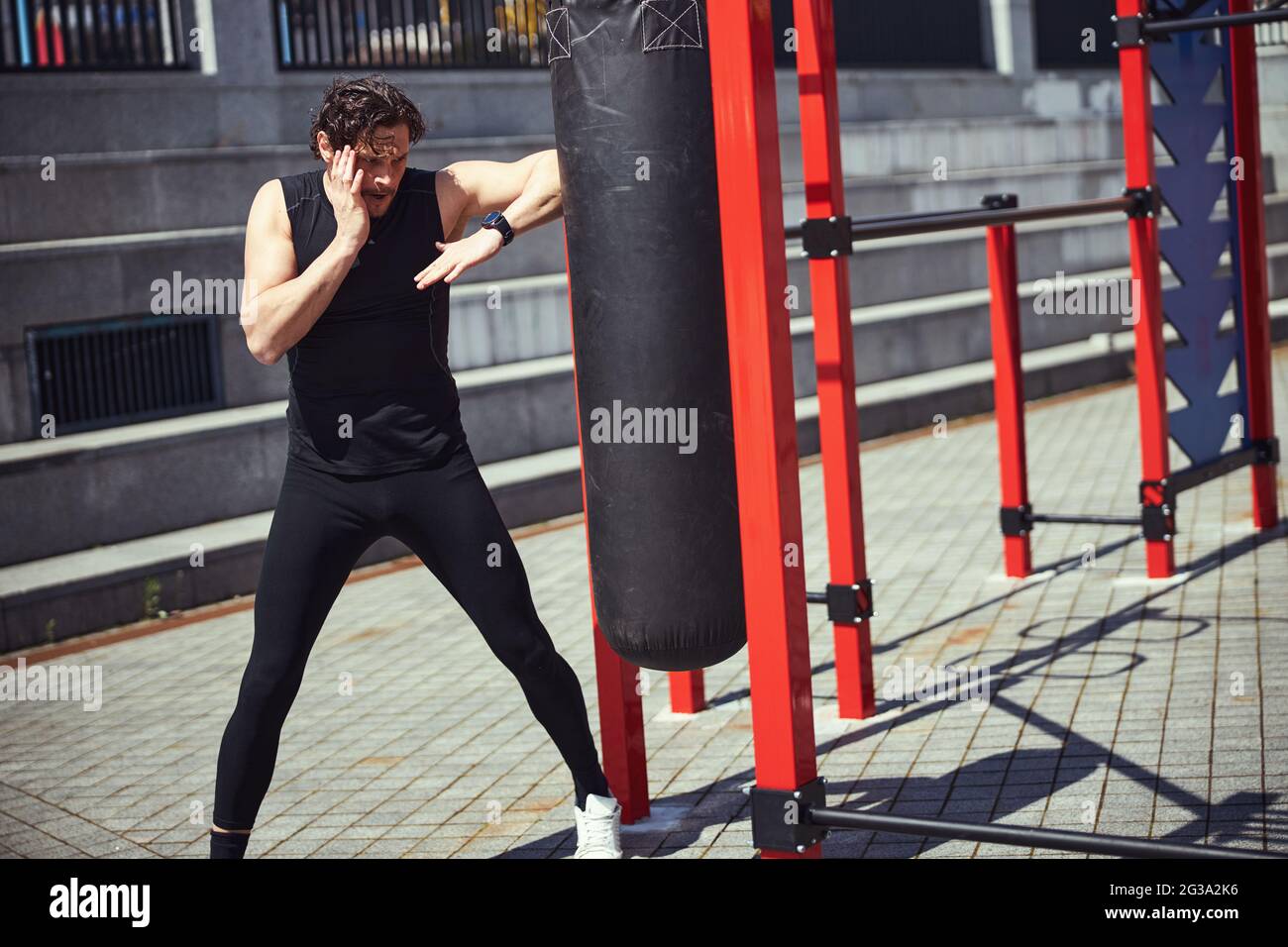 Active athlete boxing punching bag on sports ground Stock Photo - Alamy