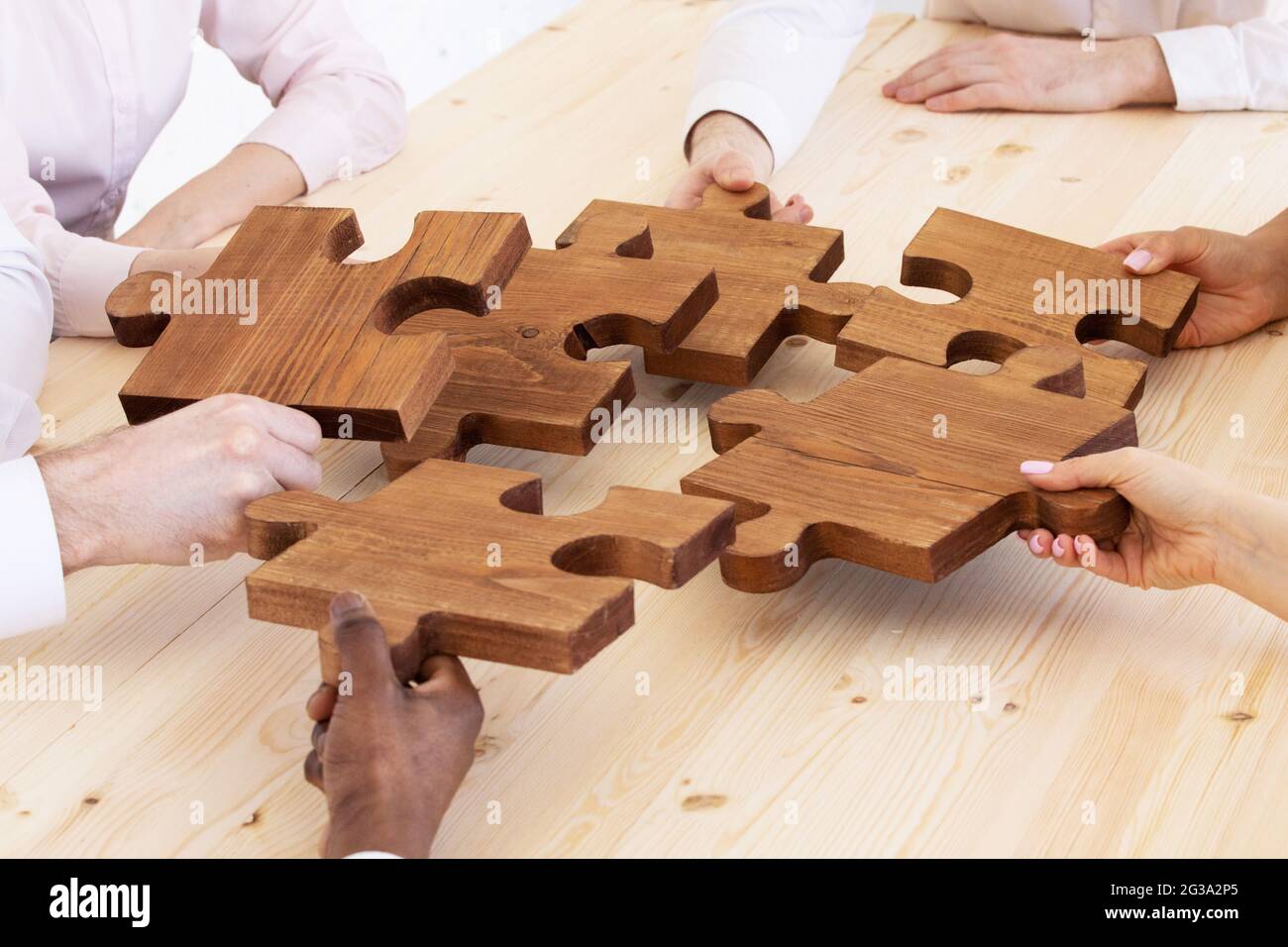 Business people team sitting around meeting table and assembling wooden ...