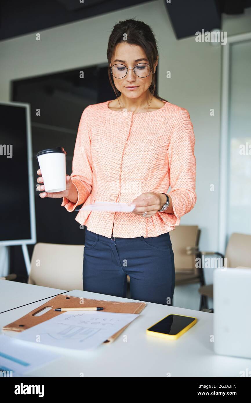 Young Caucasian focused female assistant standing near the work desk ...