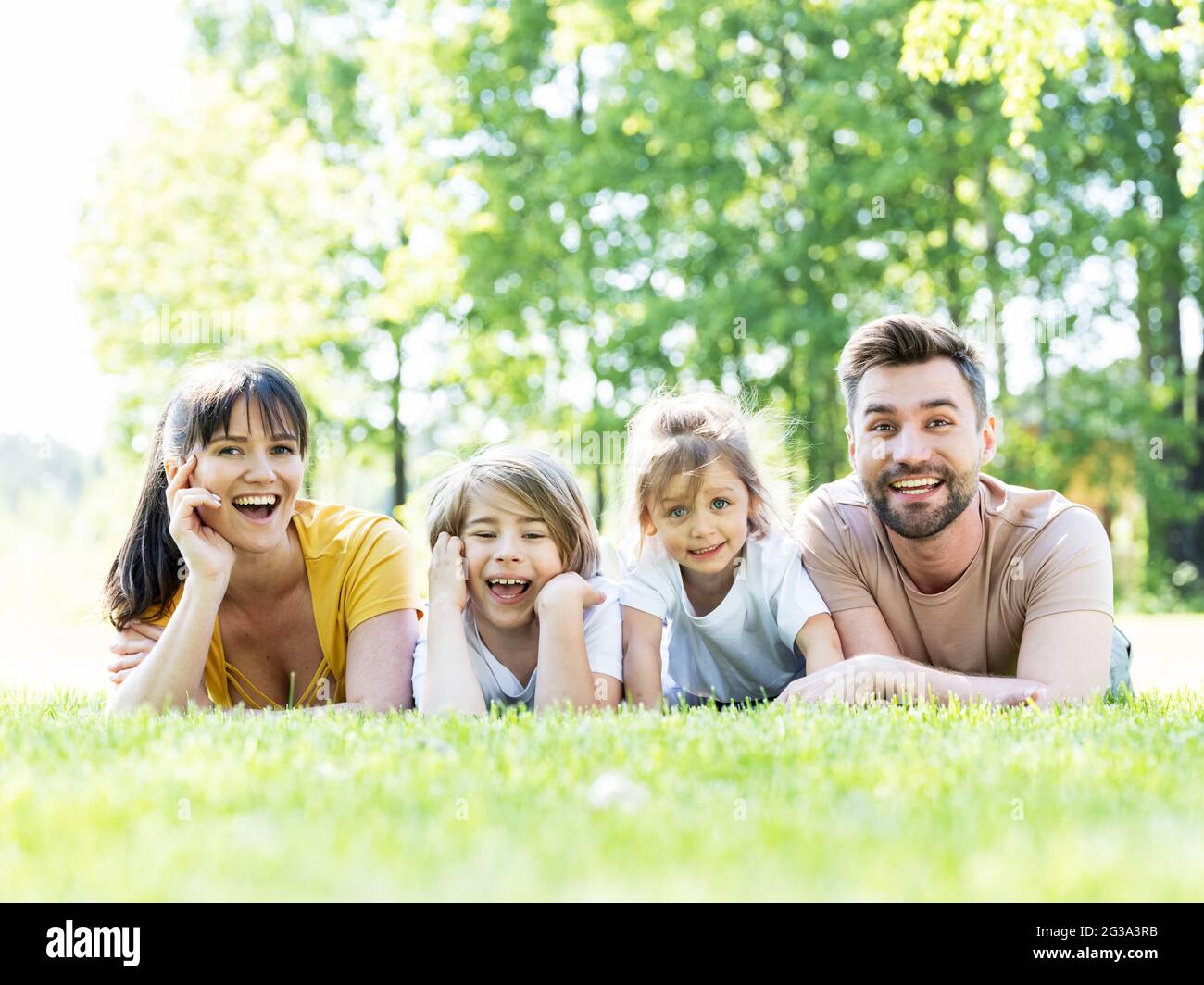 Portrait of happy family of four people lying down in grass Stock Photo ...