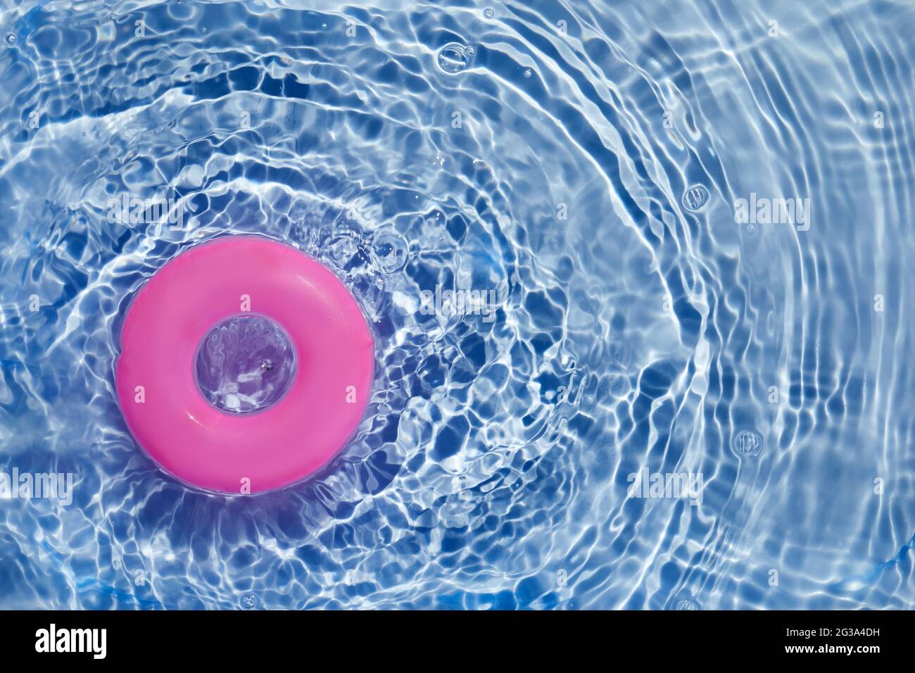 Pink pool float ring floating in a refreshing blue swimming pool. Top ...