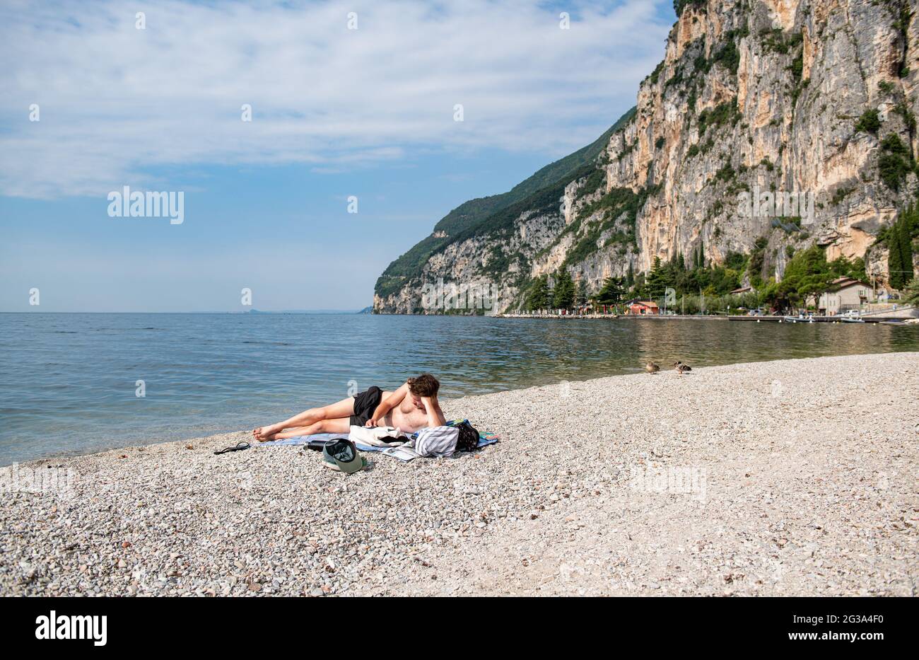 Tignale, Italy. 14th June, 2021. A man is reading a book on the beach ...
