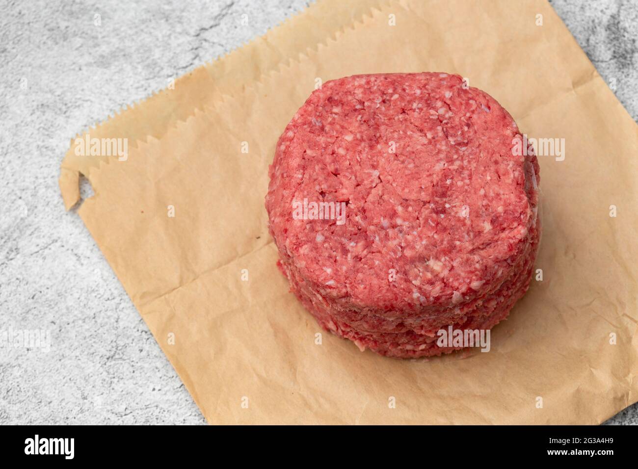 Raw beef burgers stacked on a brown paper bag. Environmentally friendly ...