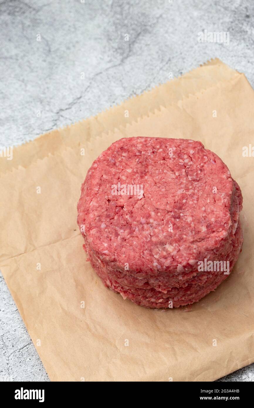 Raw beef burgers stacked on a brown paper bag. Environmentally friendly ...