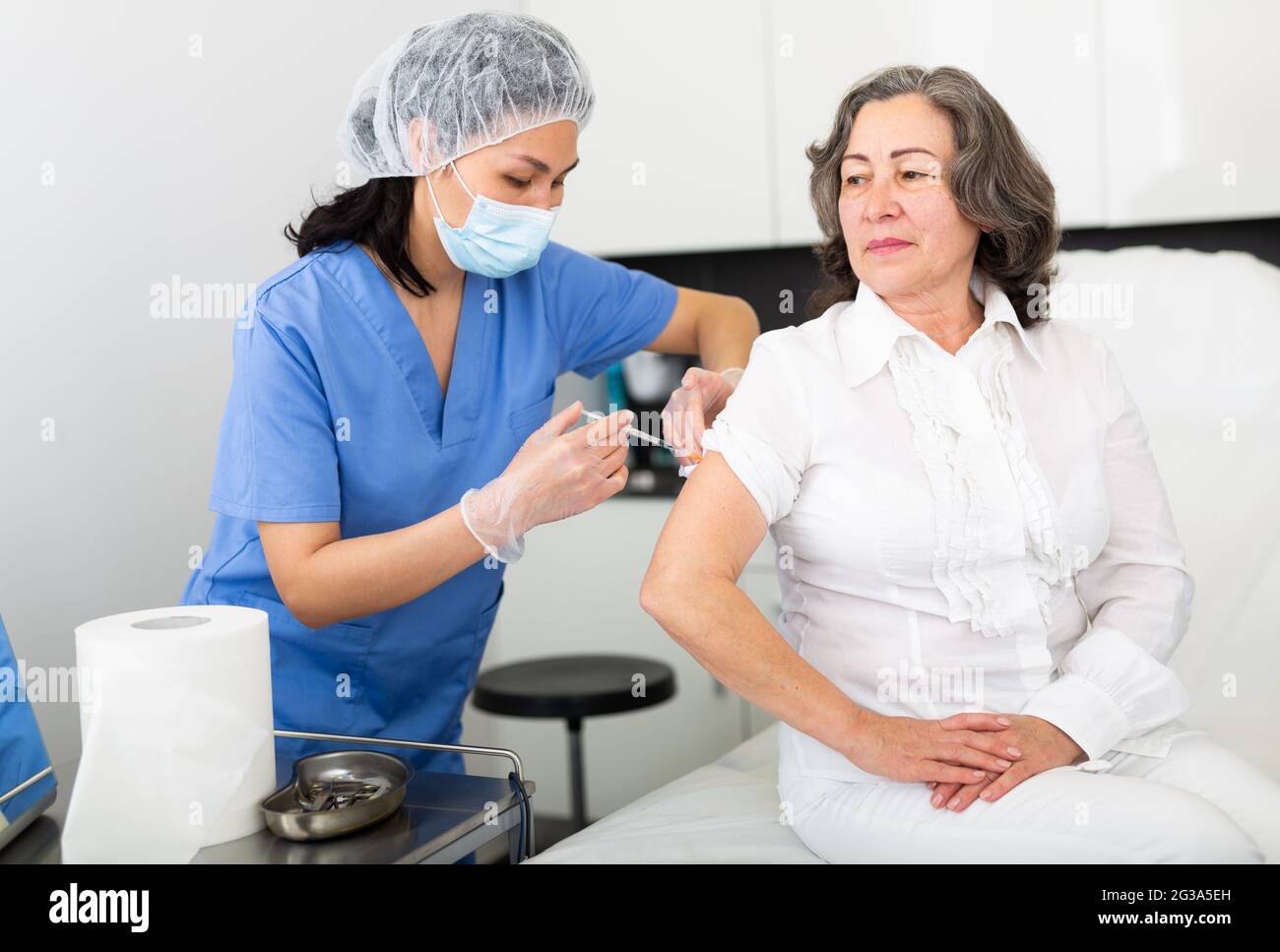 Professional female nurse injecting vaccine in shoulder of female ...