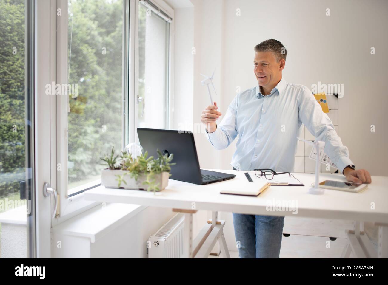 Businessman with blue shirt stands by high table and works with ...