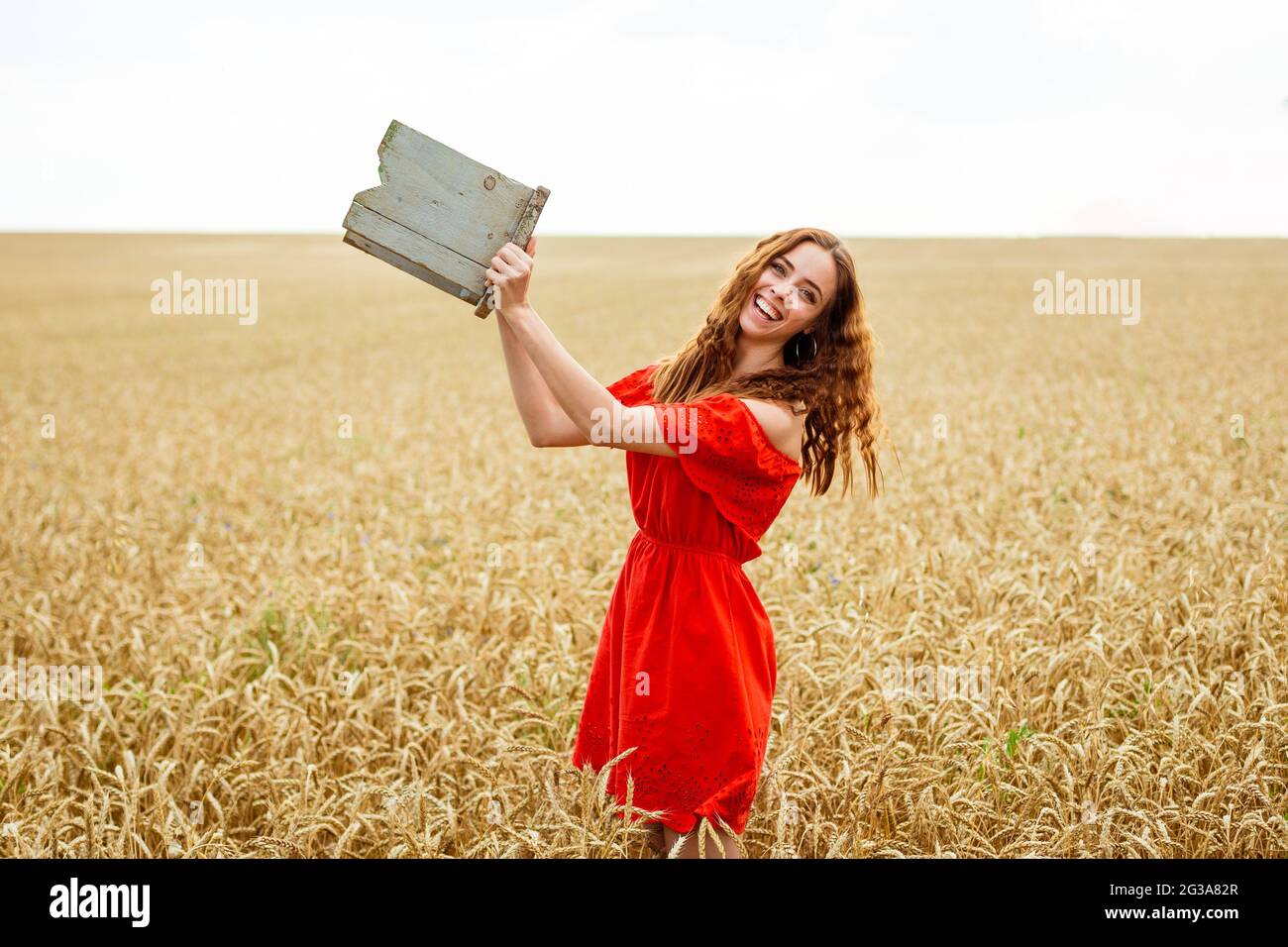 Style redhead young woman in red dress tay view yellow wheat field ...