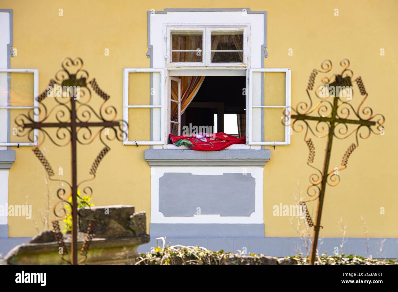 Old crosses on graves under the open window of a building with a ...