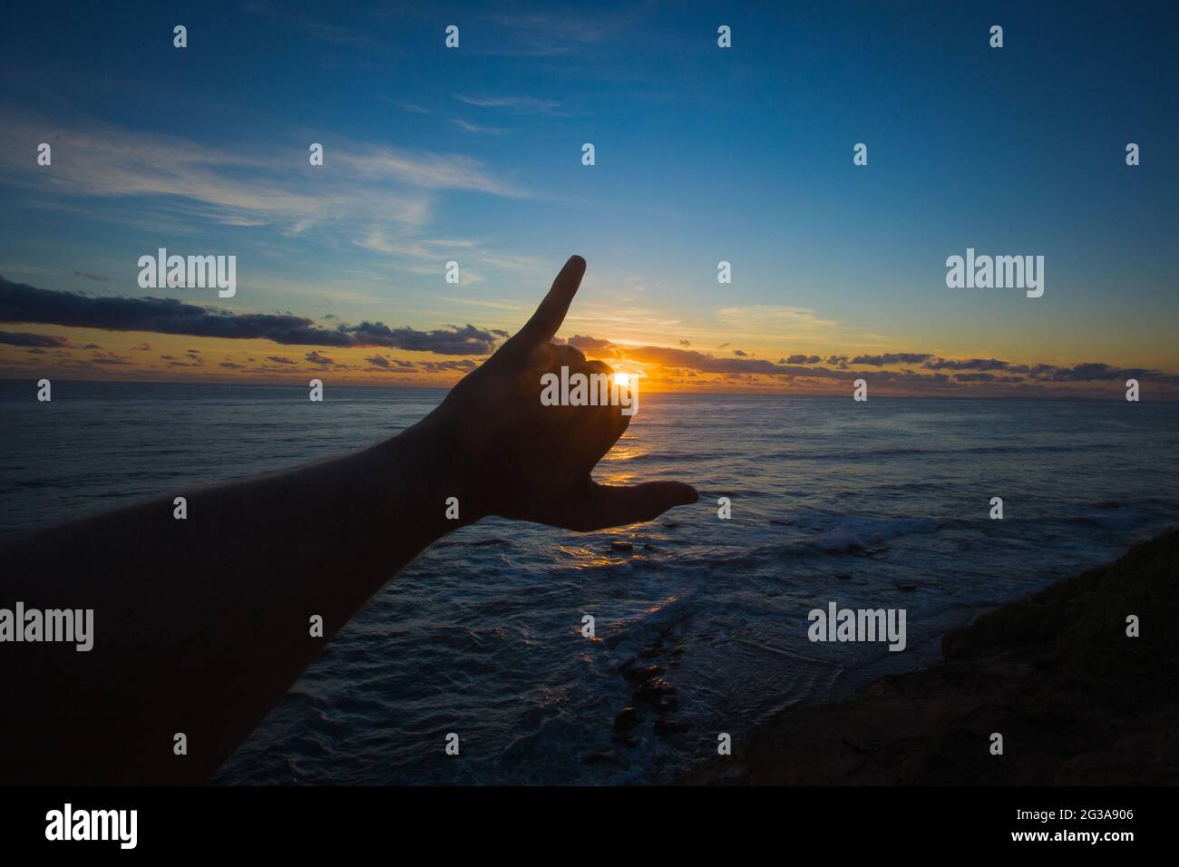 Silhouette of a hand reaching for the sun at sunset and showing the ...