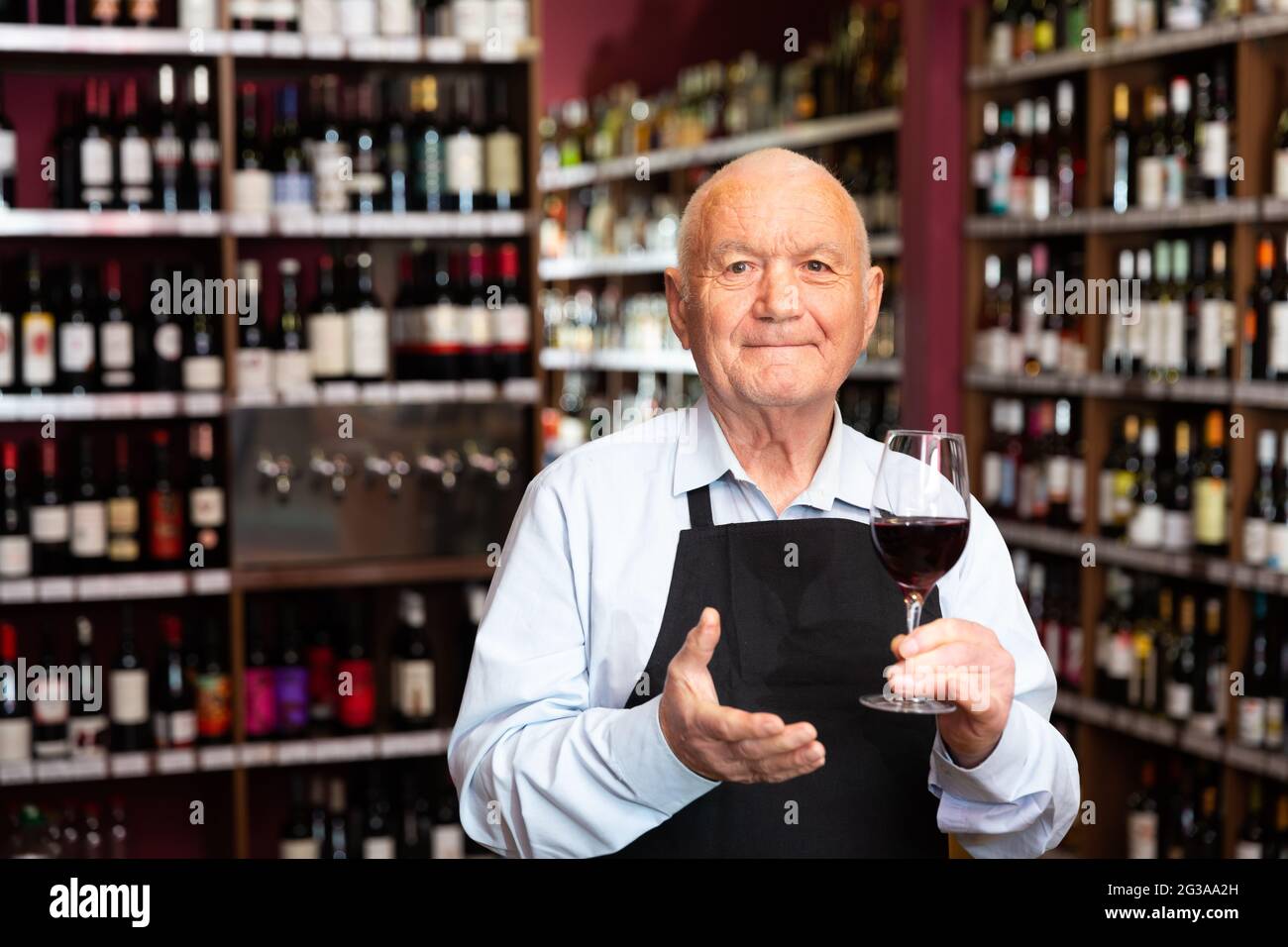 Successful elderly male owner of winery inviting to tasting wine of own ...