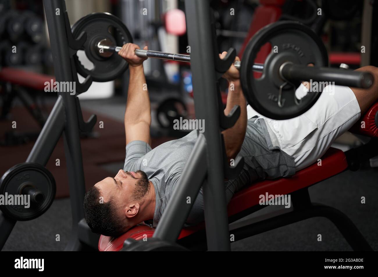 Man doing barbell bench press in the fitness gym Stock Photo - Alamy
