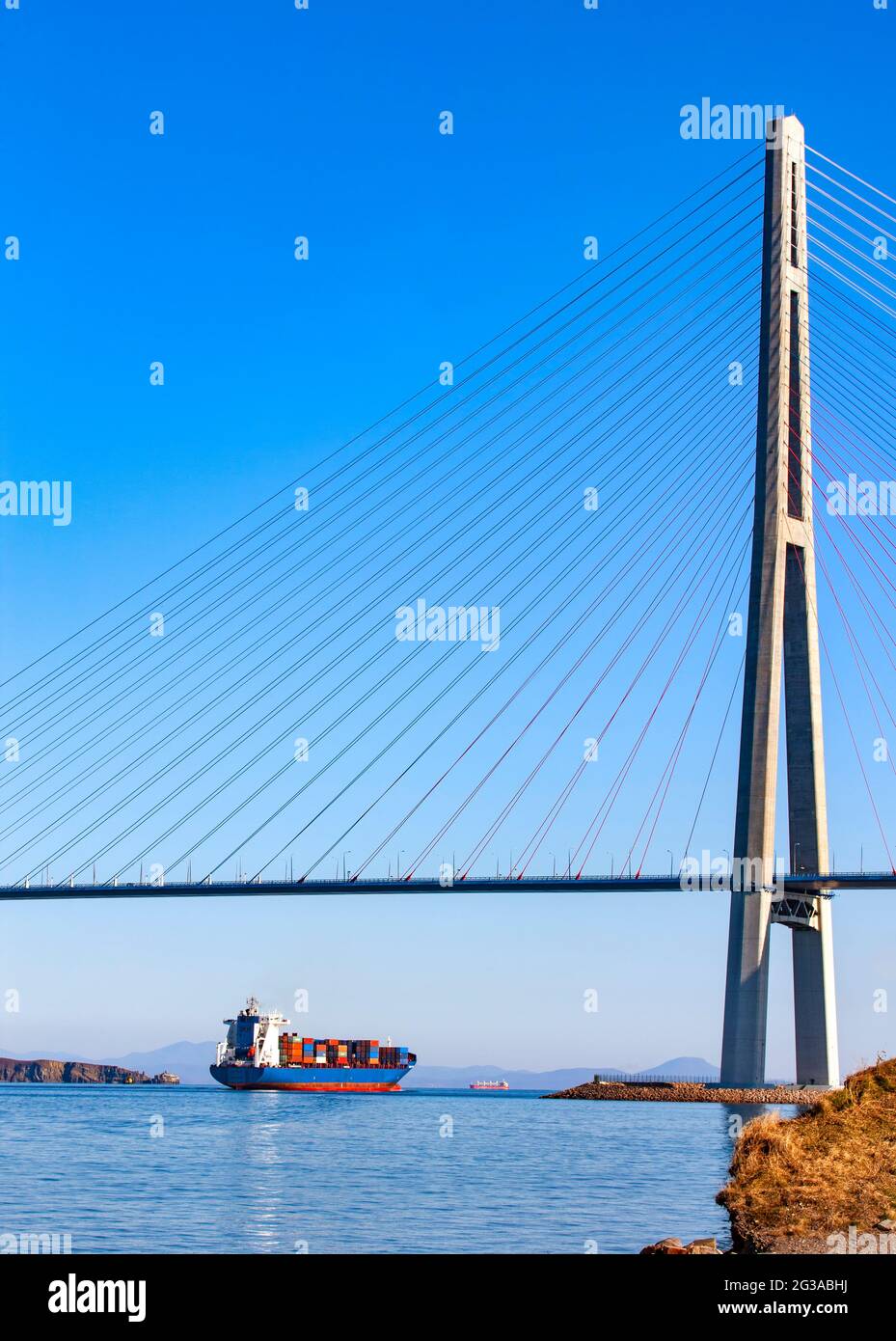The Large container ship at blue sea under the bridge Stock Photo - Alamy