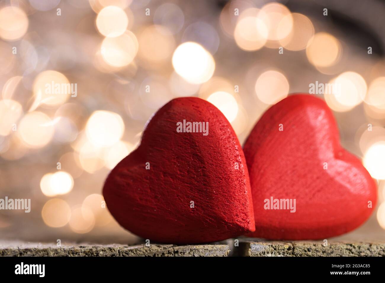 Two red wooden hearts symbol of love on background with beautiful bokeh ...