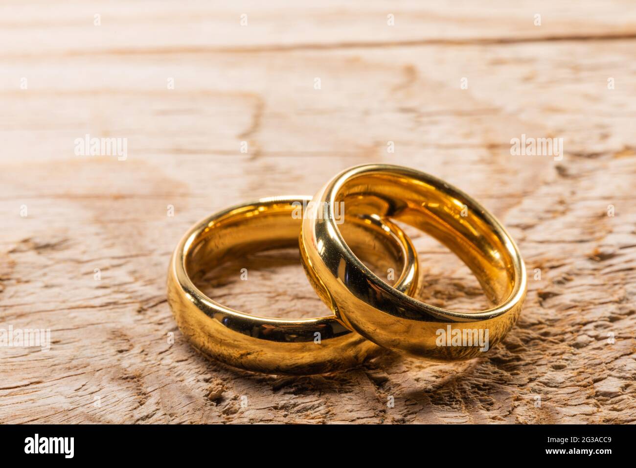 Two golden wedding rings on wooden background Stock Photo - Alamy