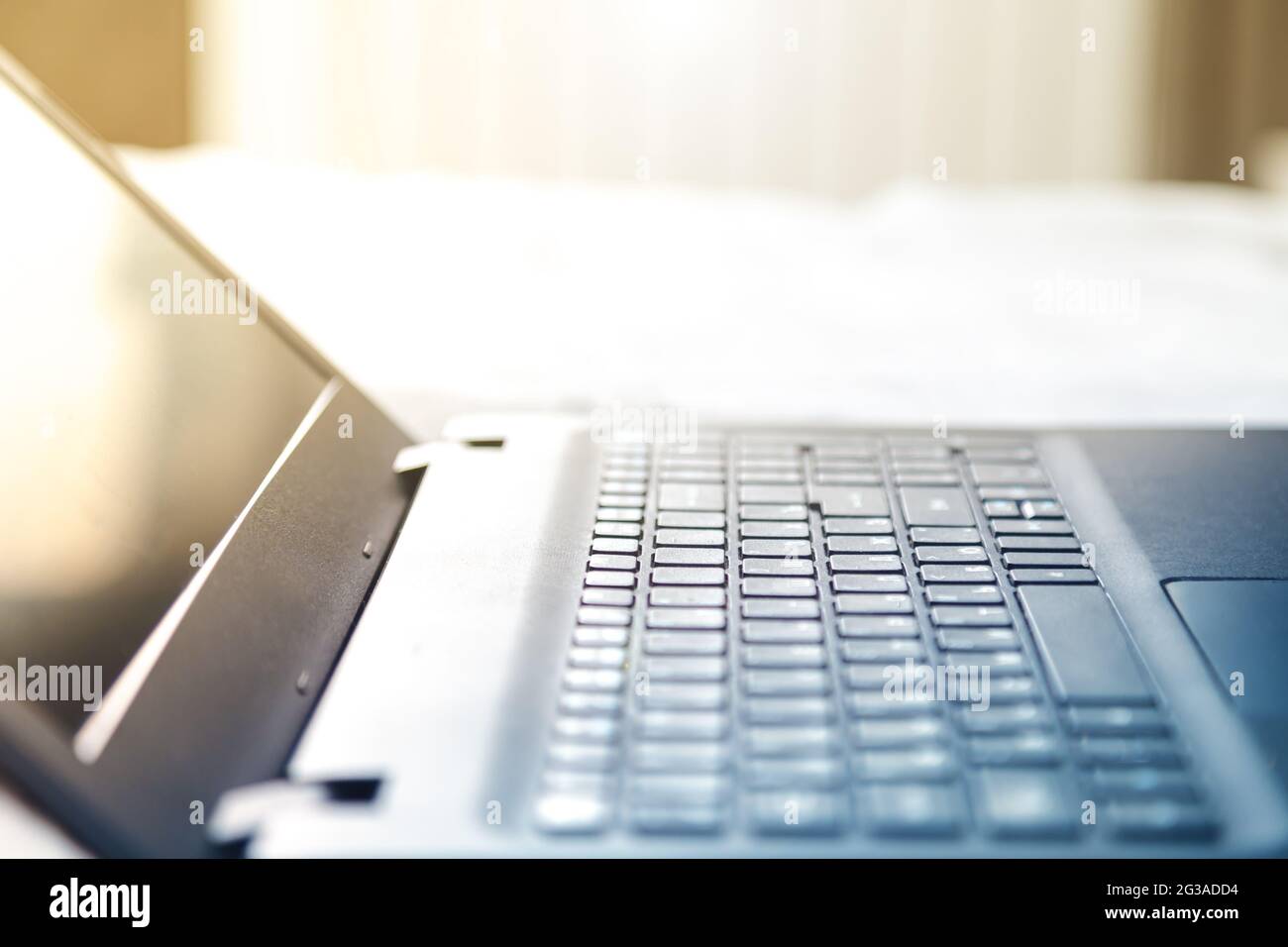 Opened black laptop, side view. Selective focus, sunlight backlight ...