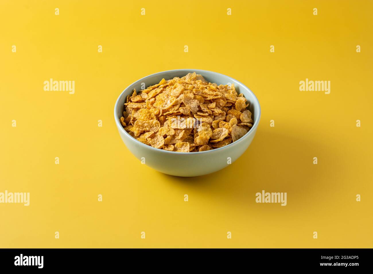 Corn flakes in a blue bowl on yellow background Stock Photo - Alamy