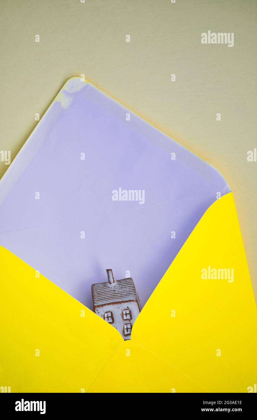 Top view of tiny ceramic house in open yellow envelope. Concept of ...