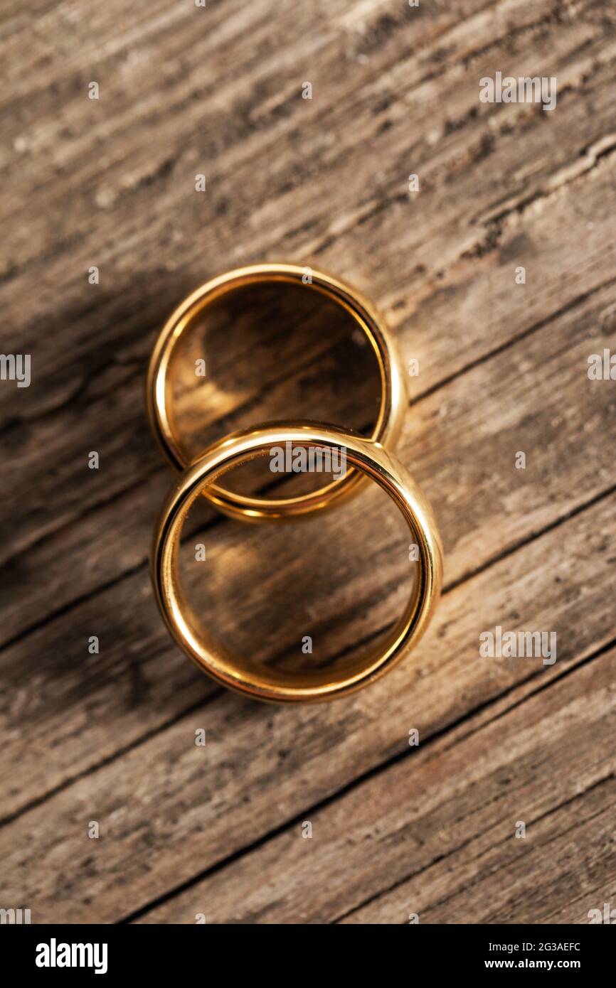 Two golden wedding rings on wooden background Stock Photo - Alamy
