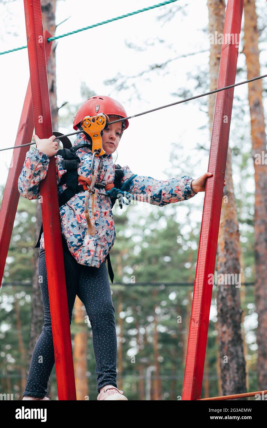 Little girl 7 years old walk on a rope rope town bridge in adventure ...