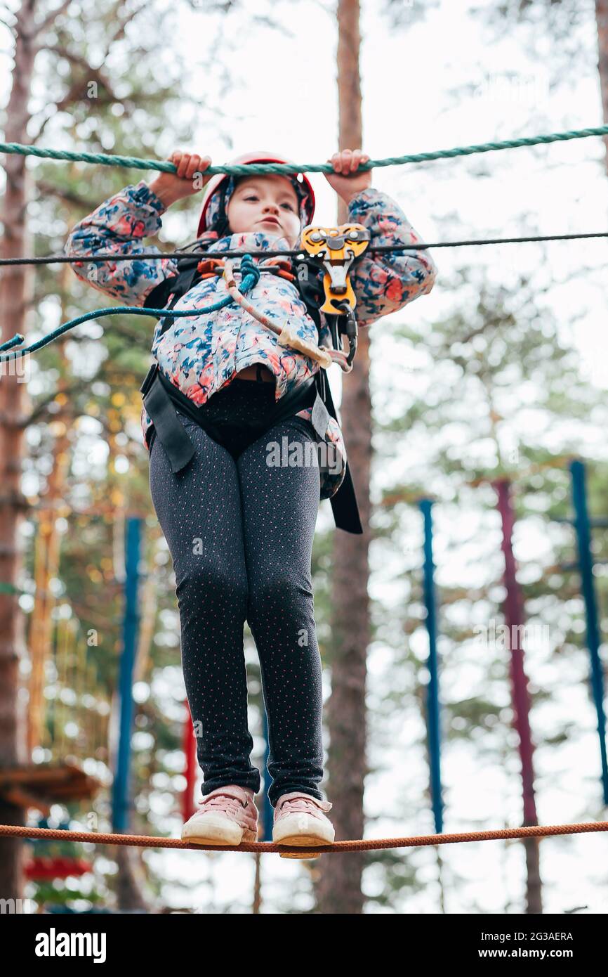 Little girl 7 years old walk on a rope rope town bridge in adventure ...