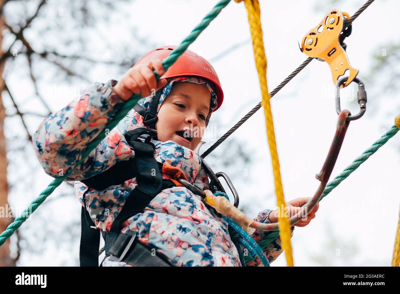 Little girl 7 years old walk on a rope rope town bridge in adventure ...