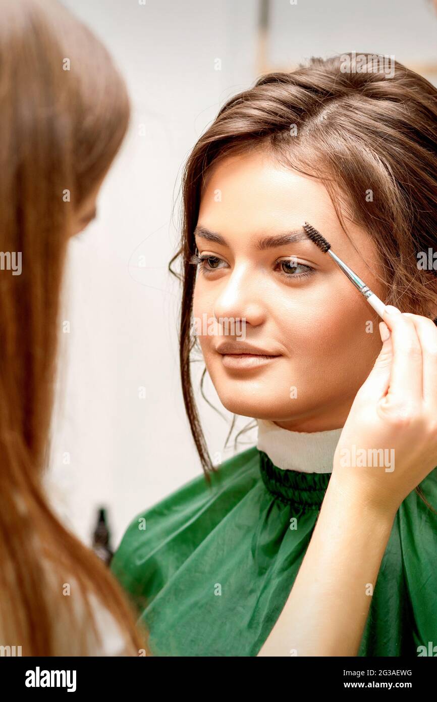 Makeup artist combing eyebrows for beautiful young caucasian bride in a ...