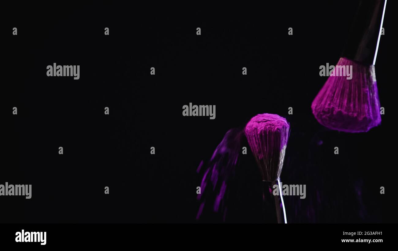 cosmetic brushes with deep purple powder on black background Stock ...